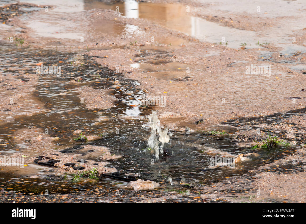 water damage to road from burst leaking water pipe Stock Photo - Alamy