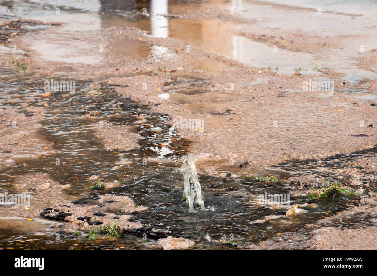 water damage to road from burst leaking water pipe Stock Photo - Alamy