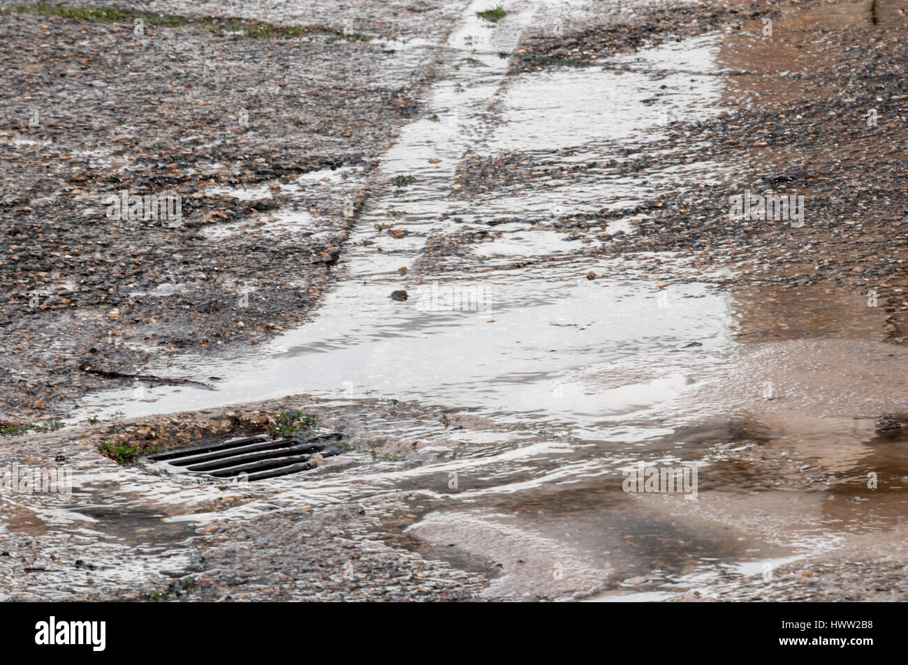 water damage to road from burst leaking water pipe Stock Photo - Alamy