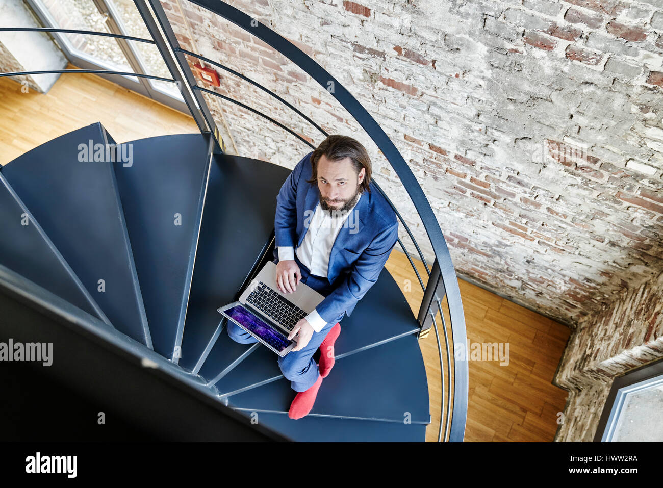 Businessman using laptop on spiral staircase Stock Photo - Alamy