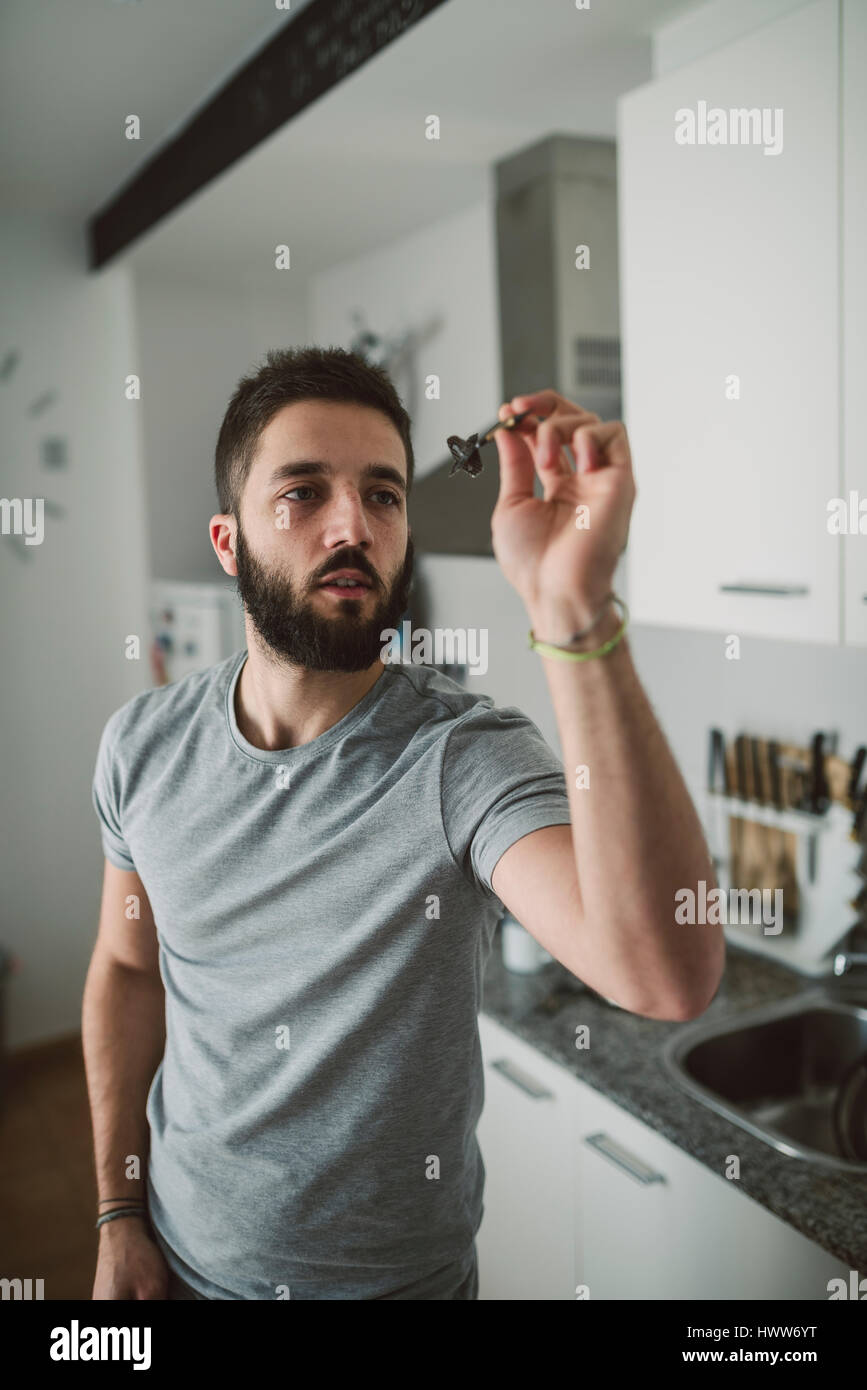 Young man playing darts in his kitchen Stock Photo - Alamy