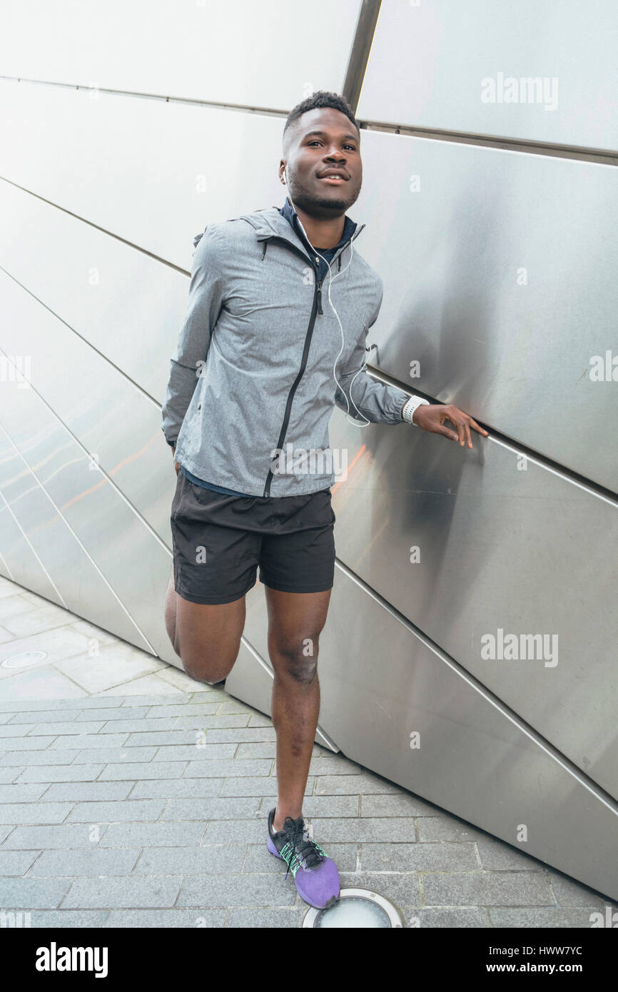 Athlete stretching at building front Stock Photo - Alamy