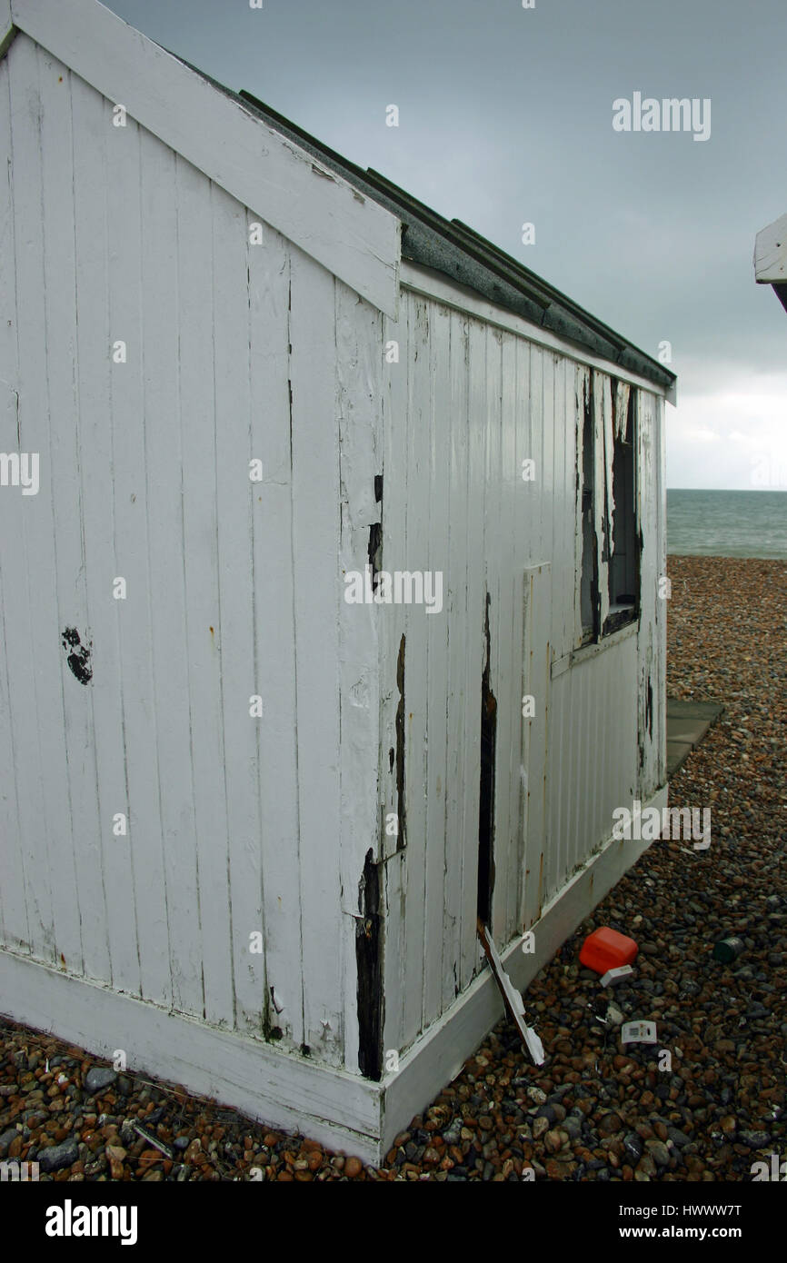 White old beach hut with some damage to the side and litter next to it ...