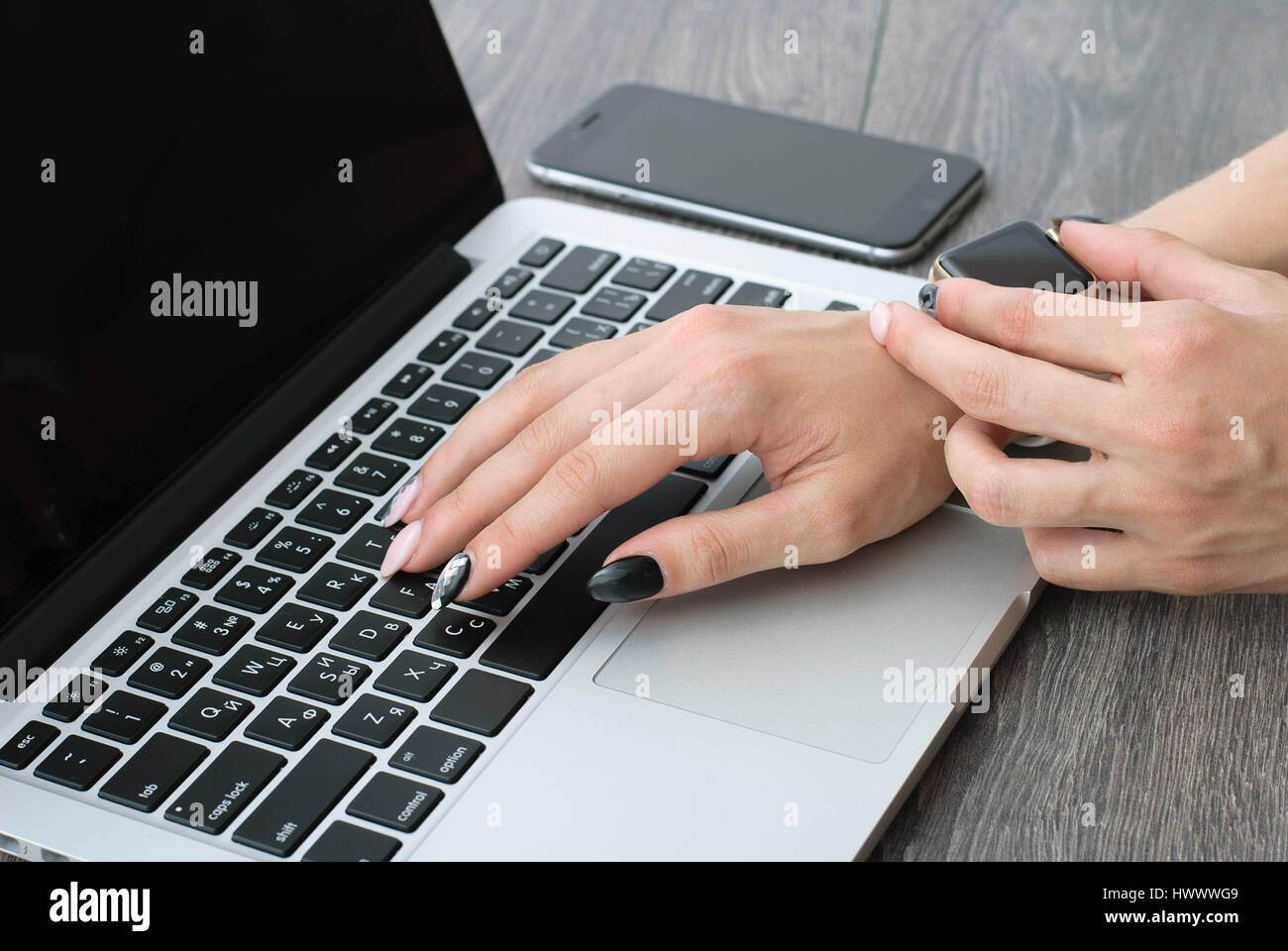 Female hand with smartwatch with holding mobile phone on laptop ...