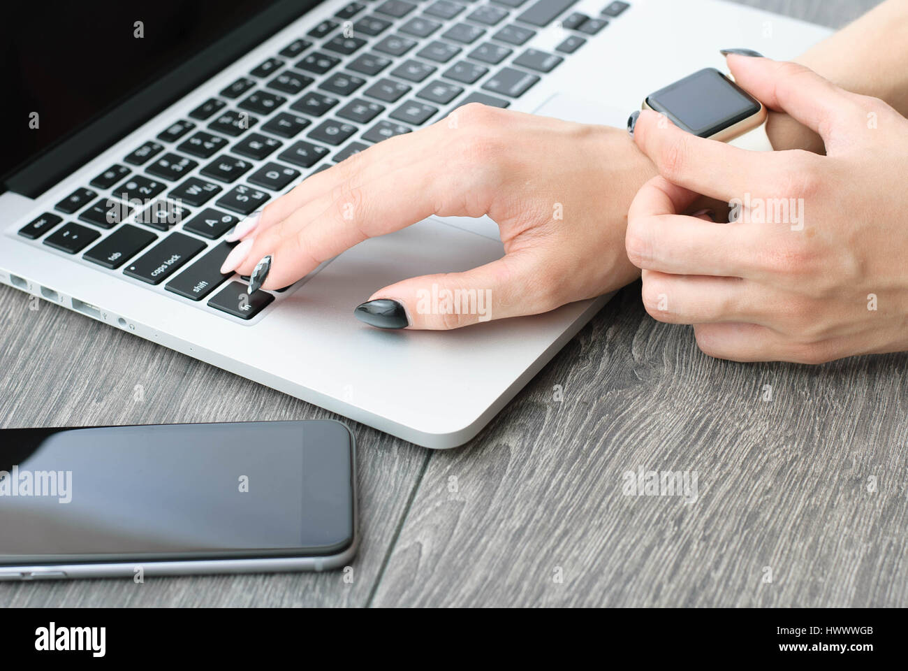 Female hand with smartwatch with holding mobile phone on laptop ...