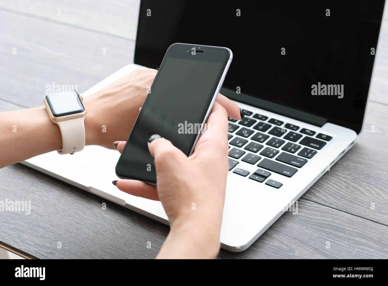 Female hand with smartwatch with holding mobile phone on laptop ...