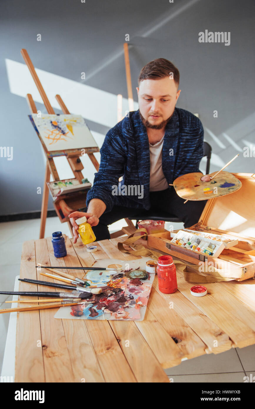 Designed by artist man finishing his masterpiece holds a brush in hand ...