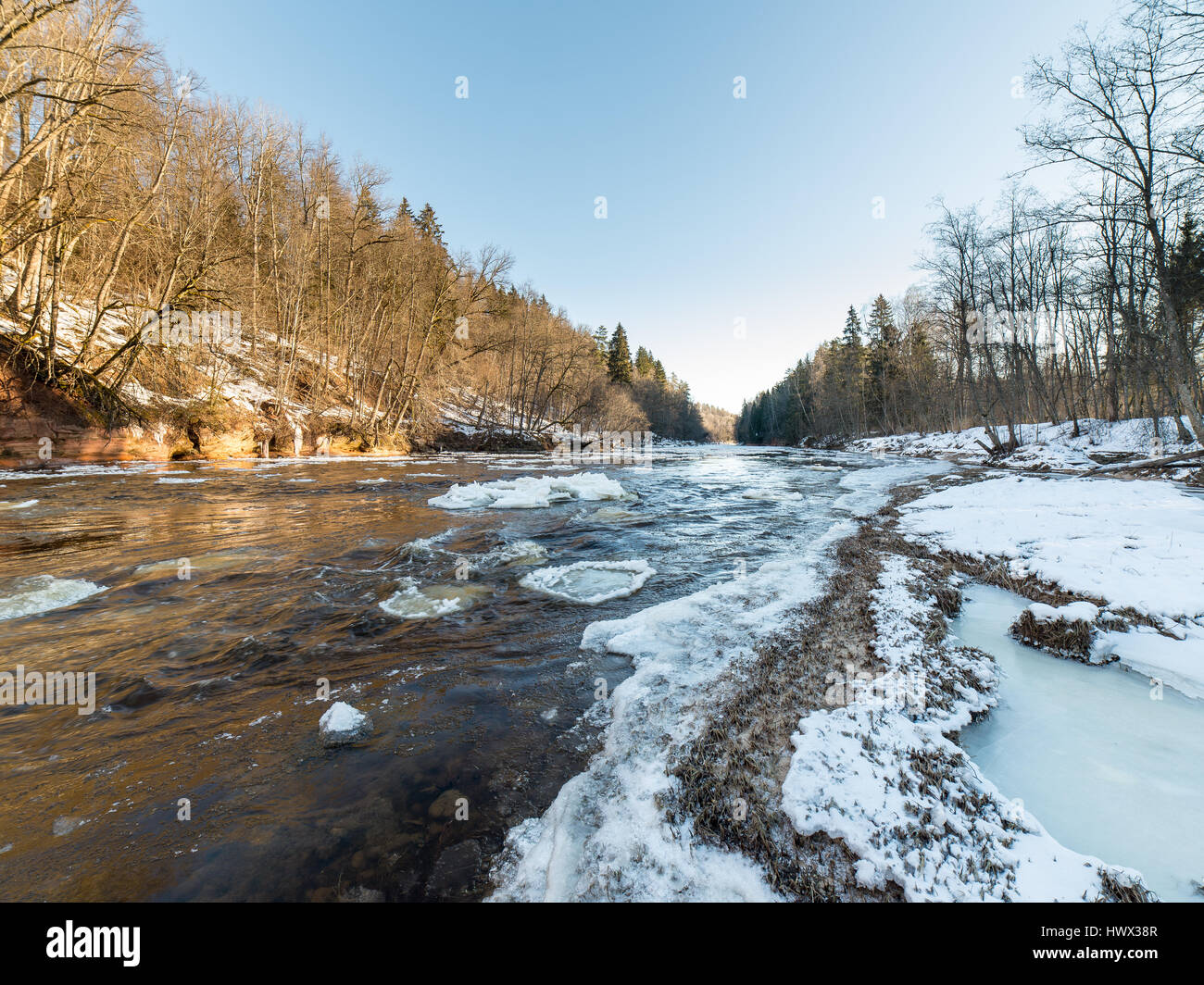 frozen river in winter with sandstone cliffs and ice blocks. Gauja ...