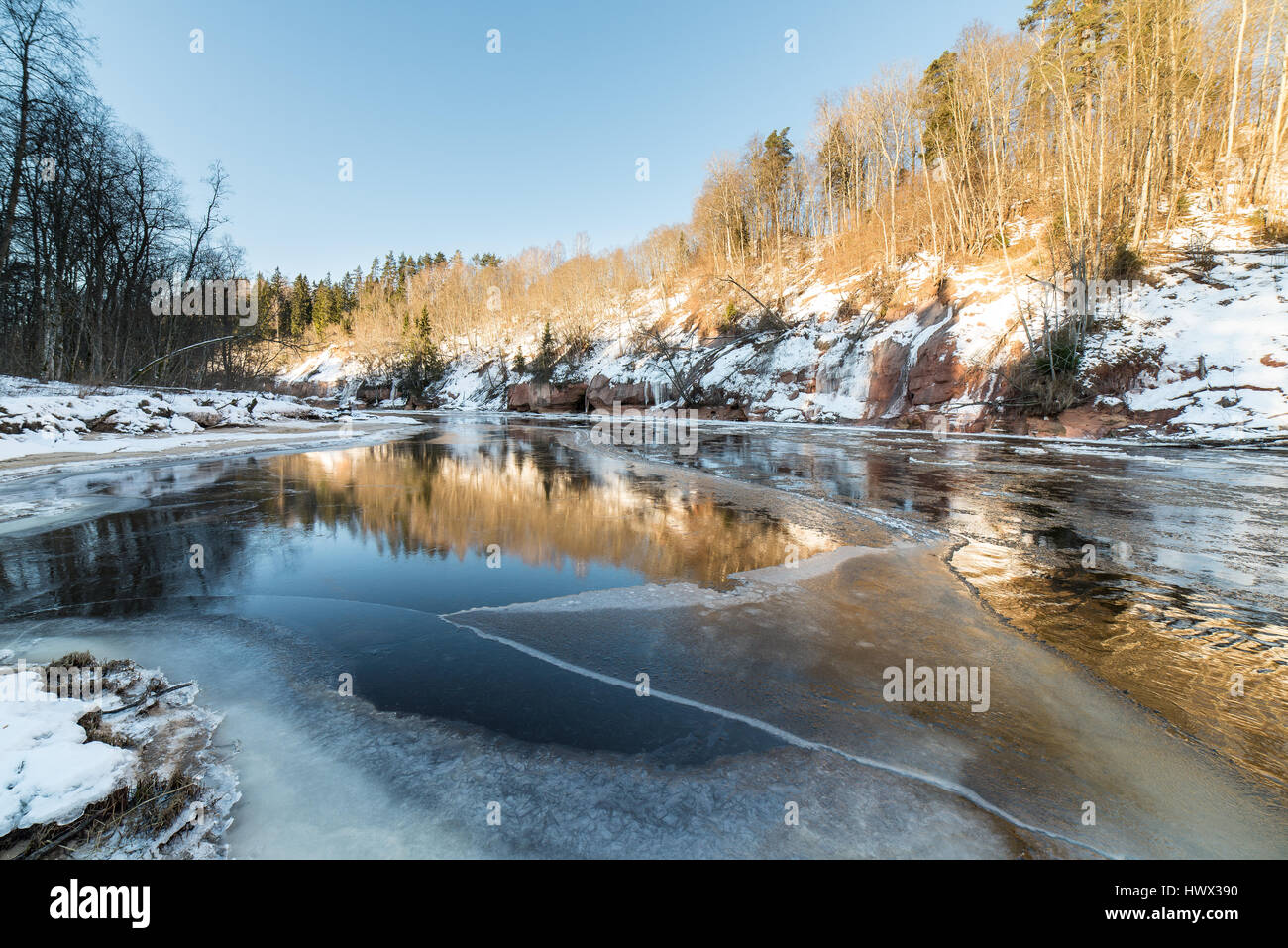 frozen river in winter with sandstone cliffs and ice blocks. Gauja ...