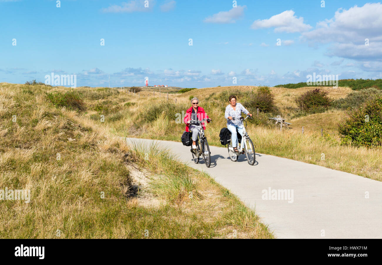 People riding bicycle on trail in dunes of national park near De ...