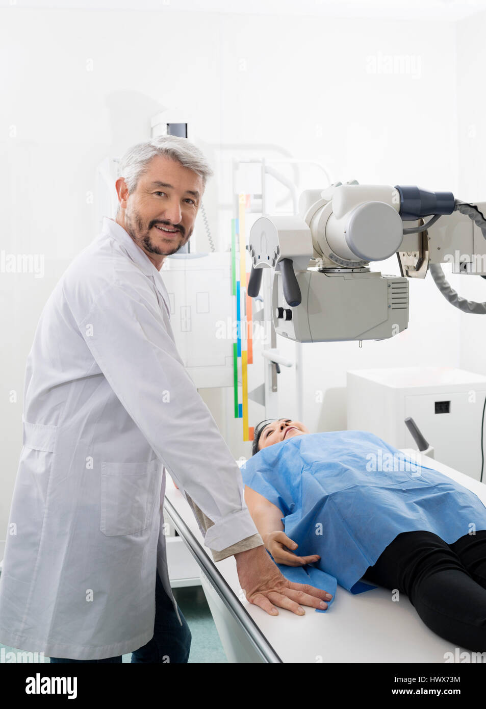 Portrait of mature male radiologist standing by female patient ...