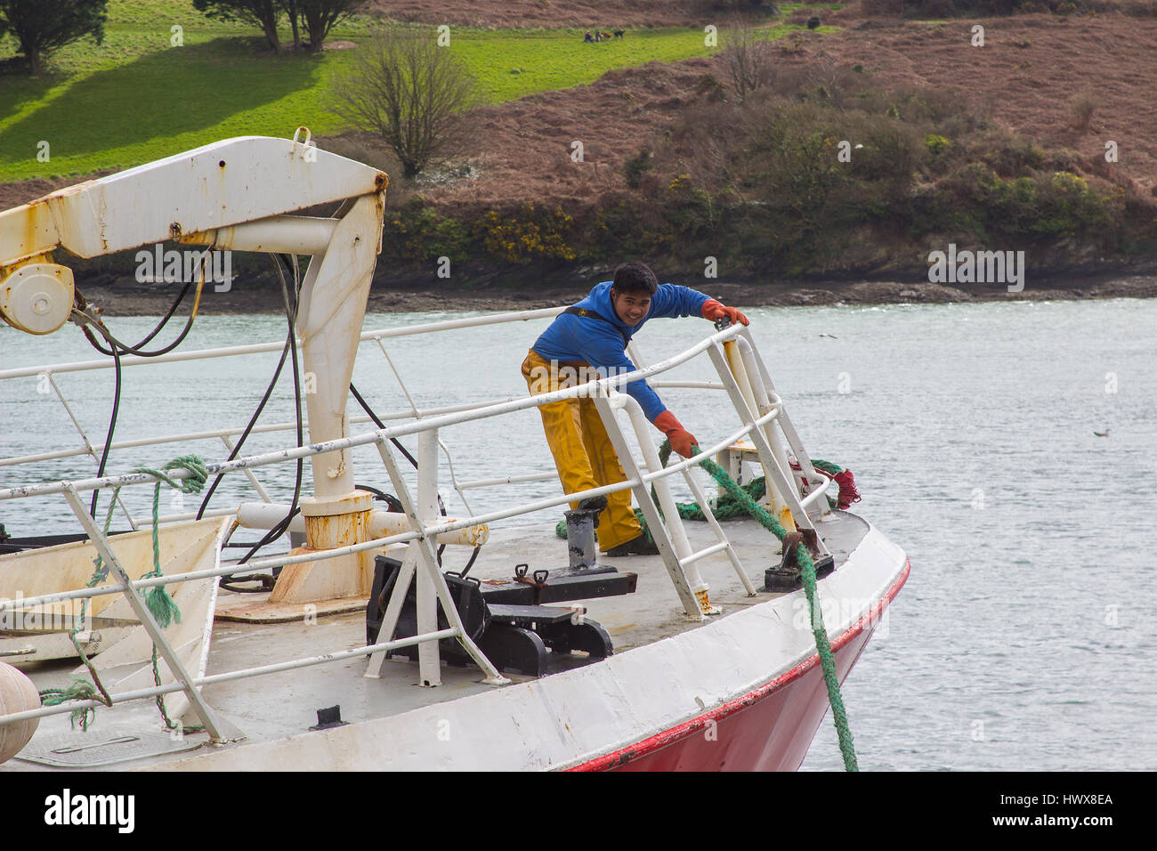 young chinese crew member hauling the mooring rope on the bow of a ...