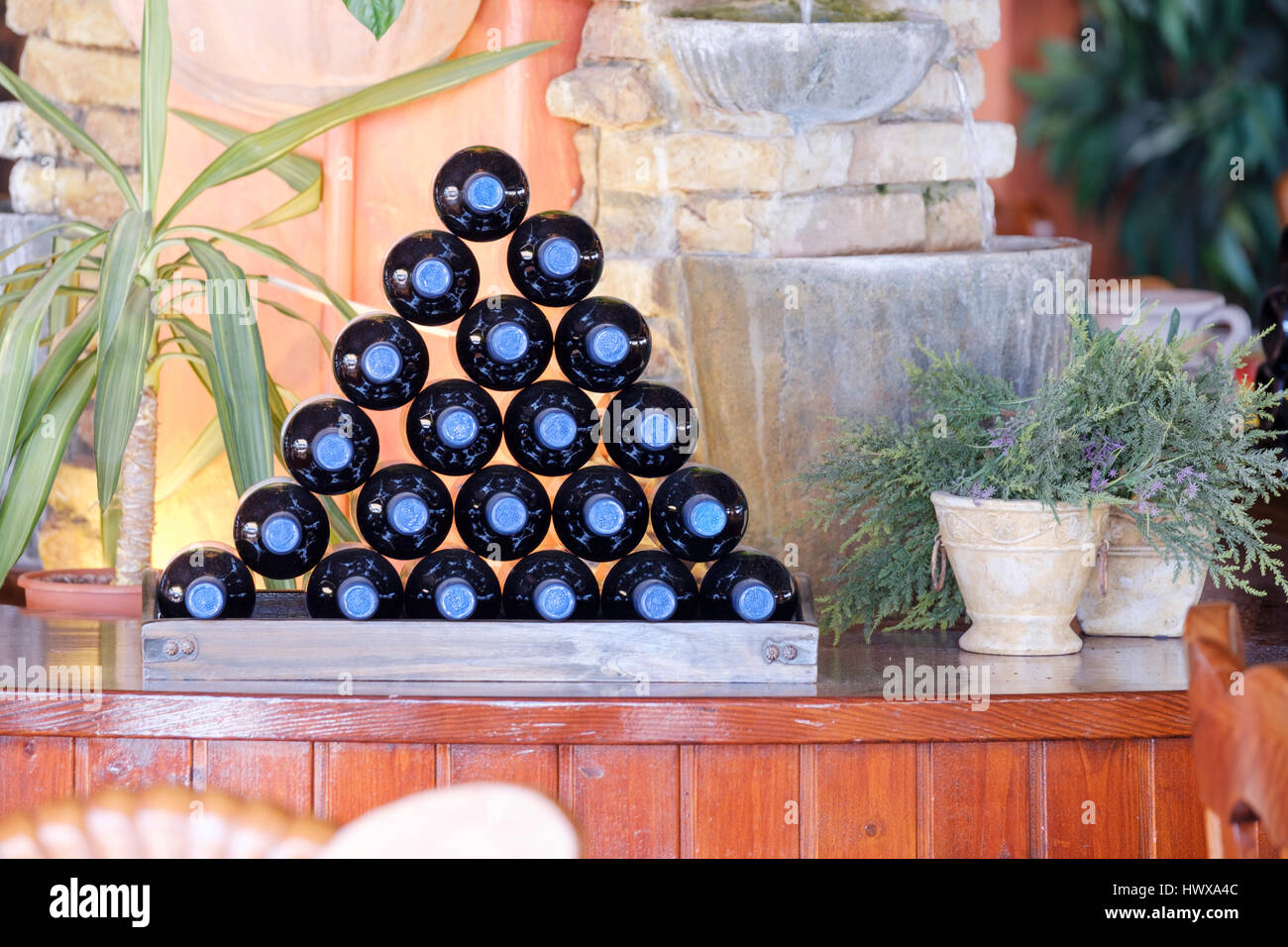 A stack of red wine bottles displayed in a triangular in a restaurant ...