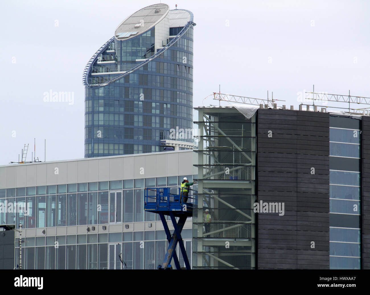 Builders working on modern tower block building from hydraulic platform ...