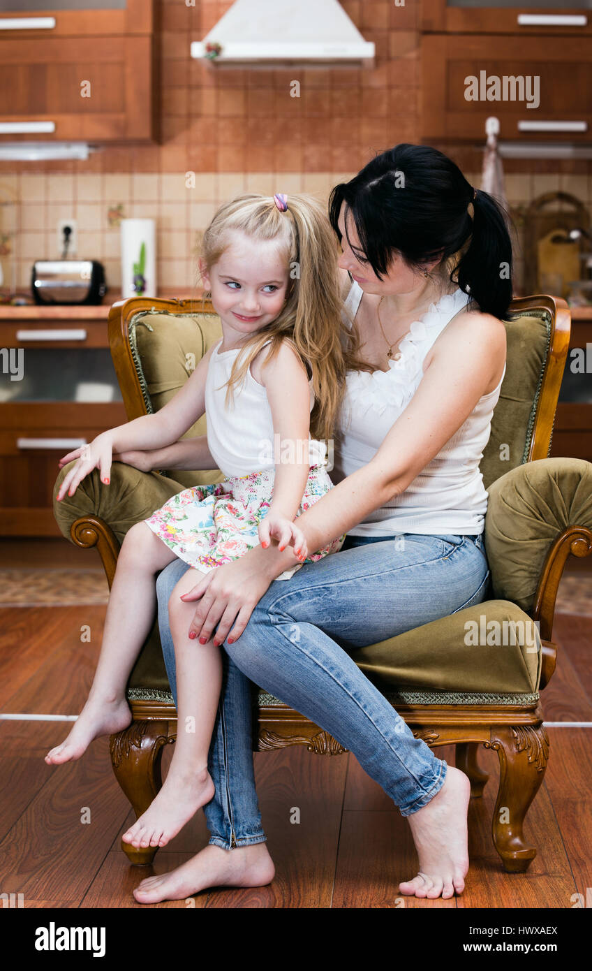 Mother and her little daughter sitting in a chair at home Stock Photo ...