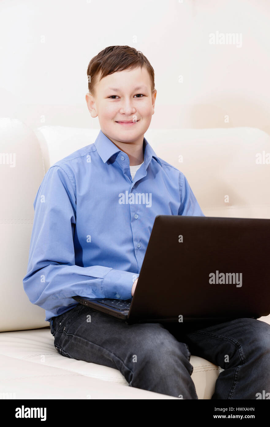 Boy sitting on sofa with laptop Stock Photo - Alamy