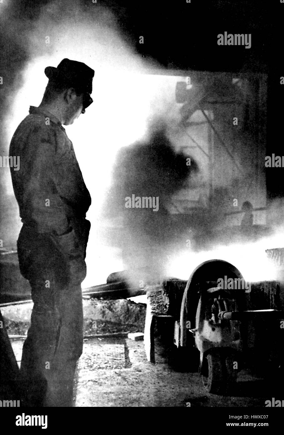A worker looks on while a large smelter is used to melt down and ...