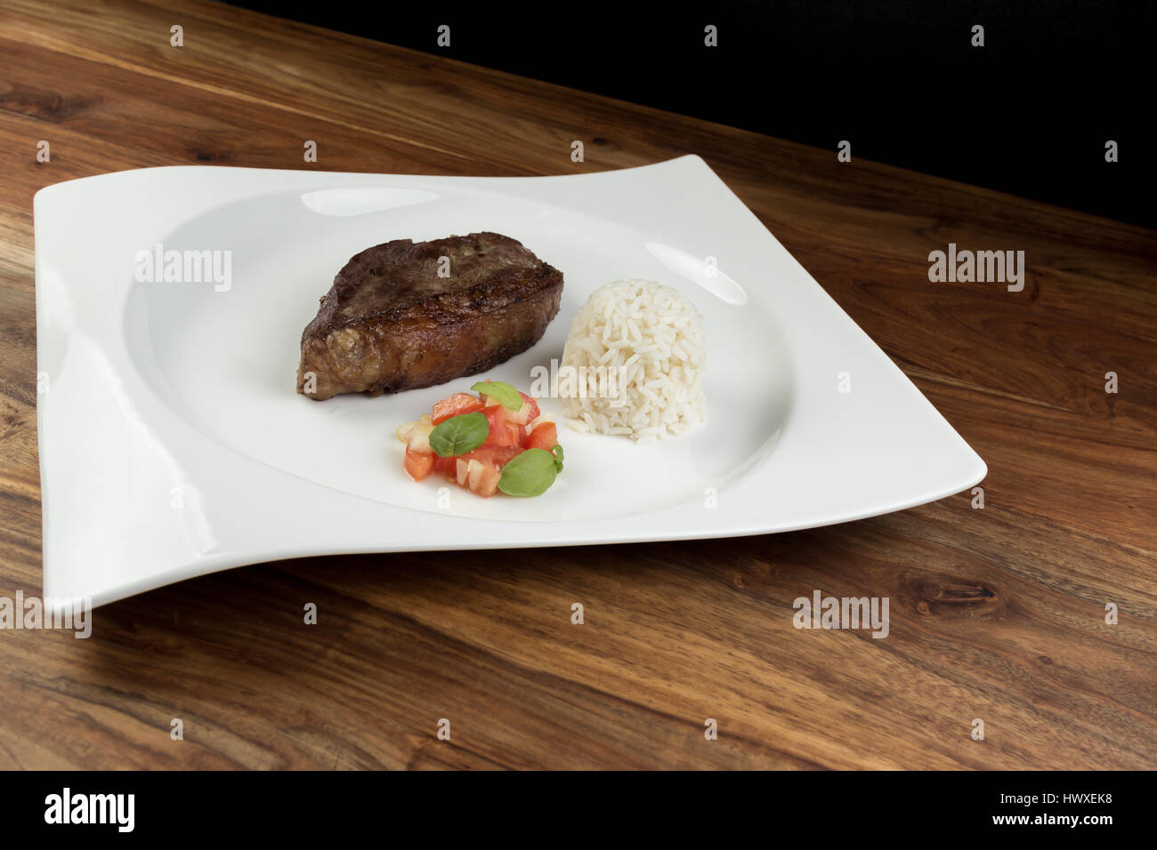 Slice of barbecued cow beef (picanha), rice and salad on a white dish ...