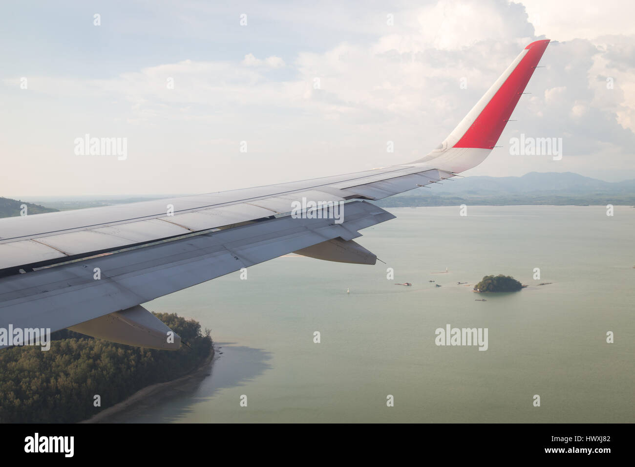 Wing of an airplane flying above the ocean and many island Stock Photo ...