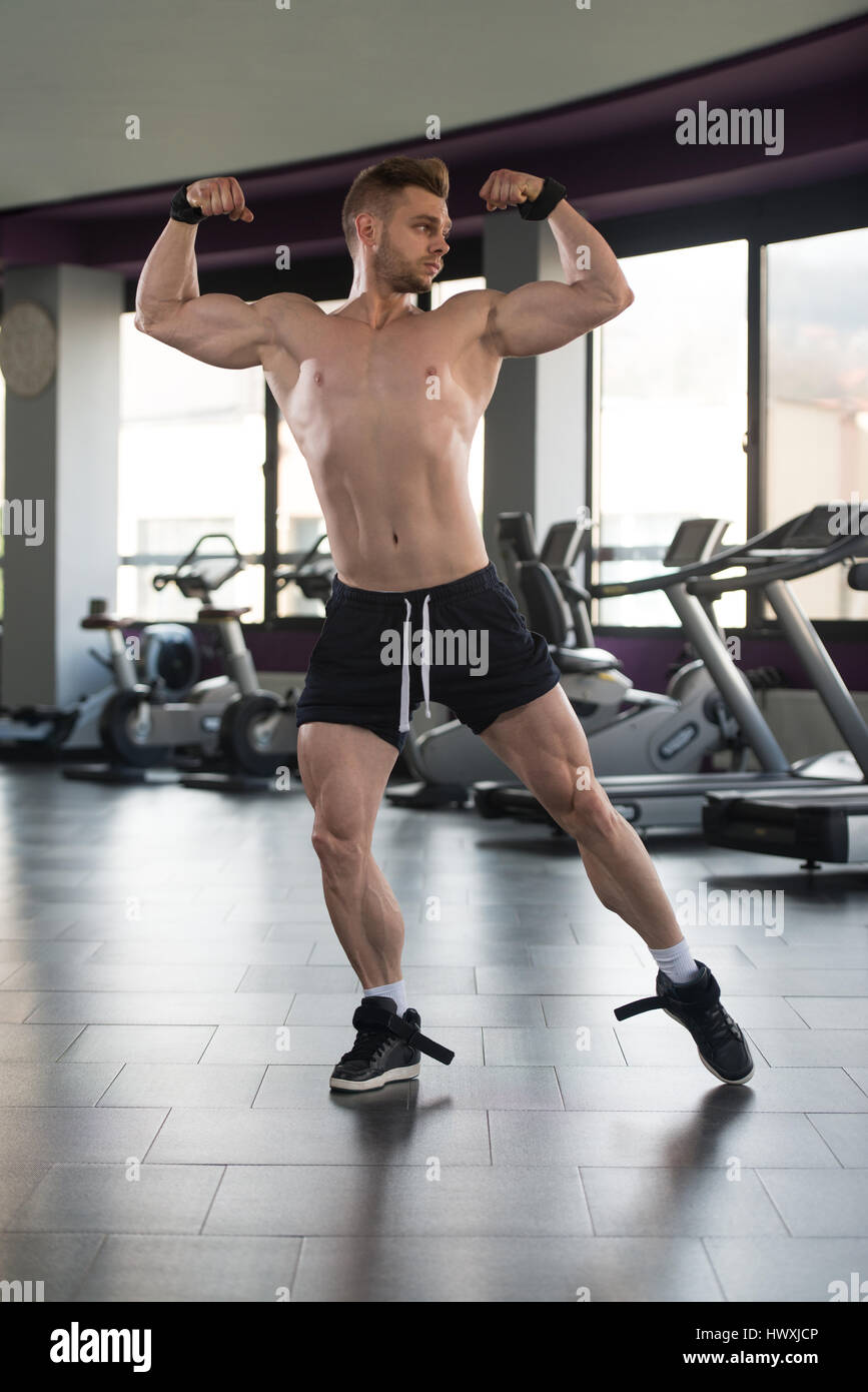 Handsome Man Standing Strong In A Modern Gym And Flexing Muscles ...