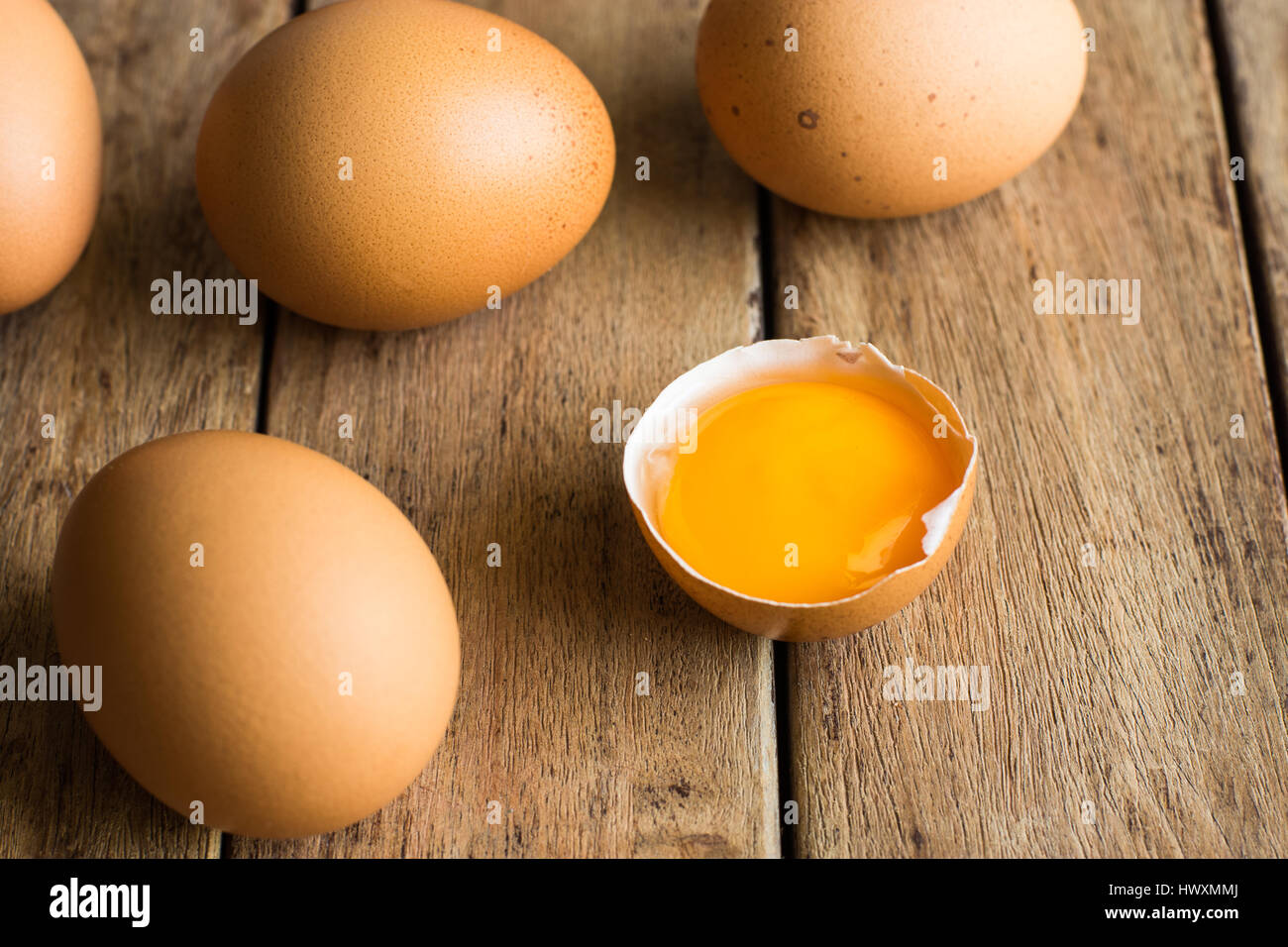 Fresh organic brown eggs scattered on wood table, open yolk ...