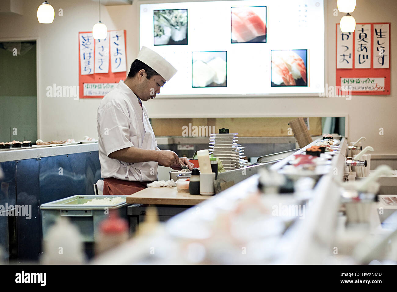 A Japanese chef preparing sushi for the running sushi restaurant in ...