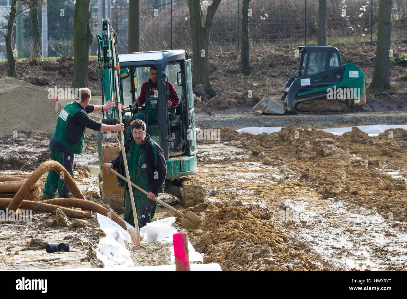 Workmen at building site digging trench Stock Photo - Alamy