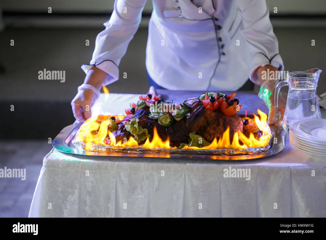 ham cooking on grill with flames. Dish served with fire chef on ...