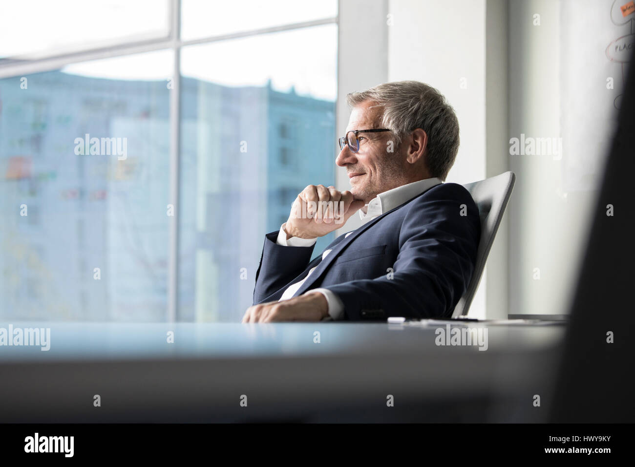 Confident businessman looking out of window Stock Photo - Alamy