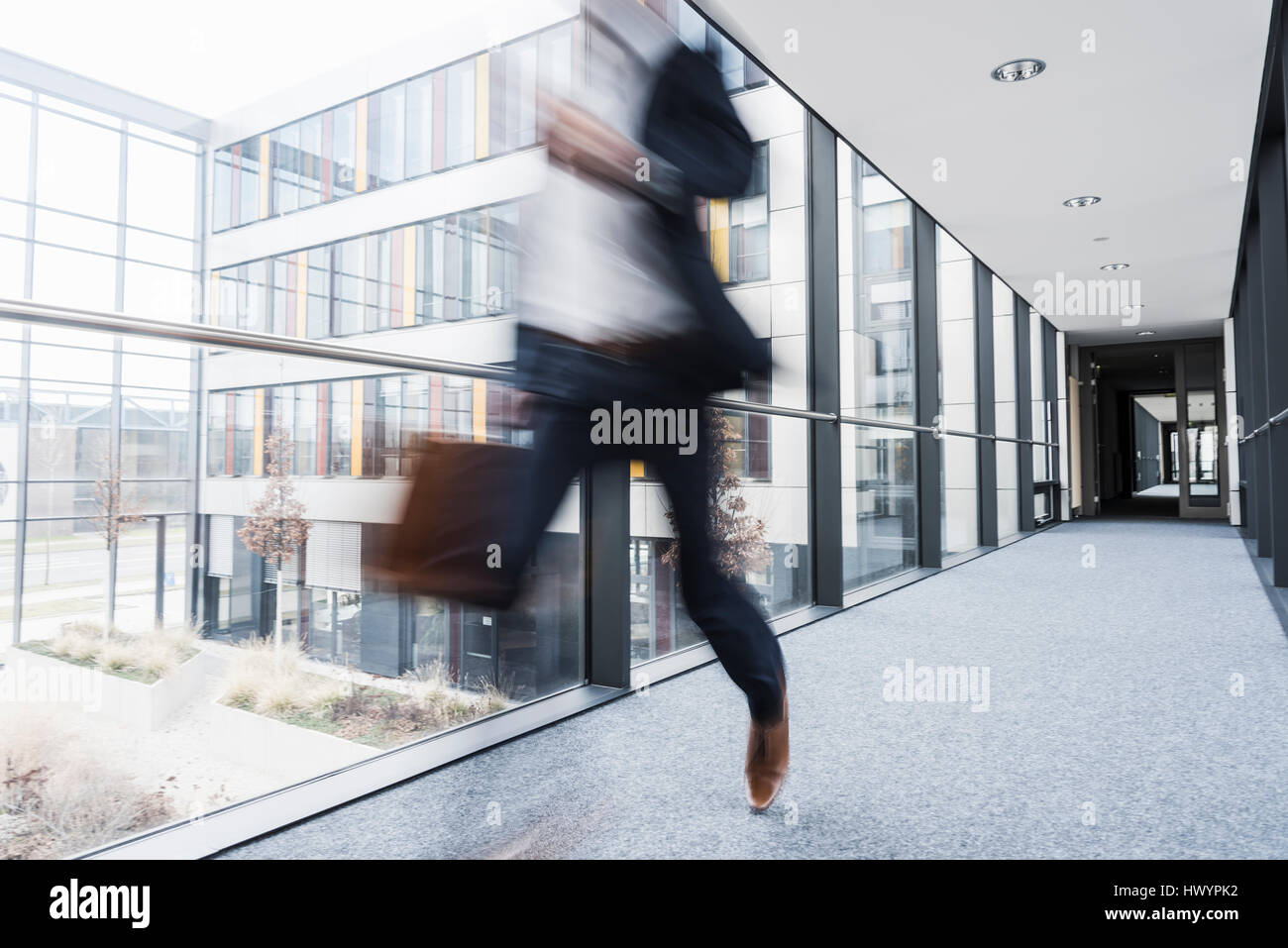 Businessman running in corridor of an office building Stock Photo - Alamy