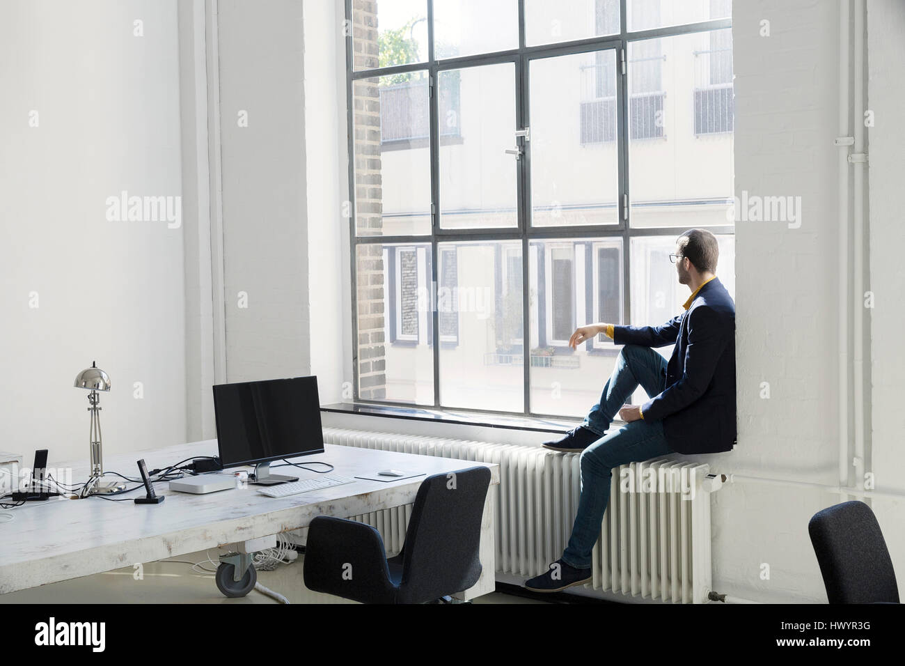 Young businessman looking out of office window Stock Photo - Alamy