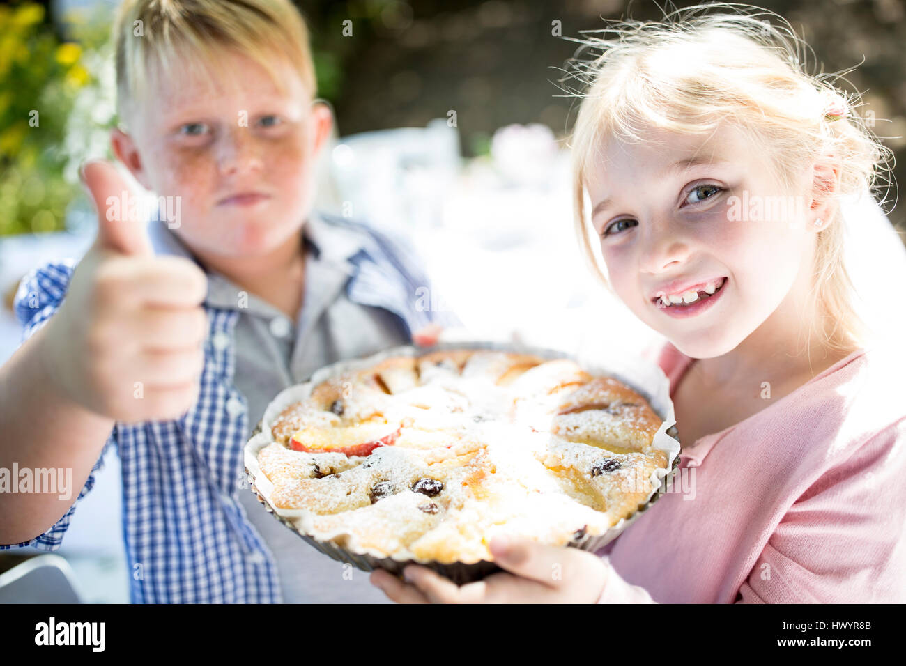 Portrait of smiling girl with brother holding a pie outdoors Stock ...