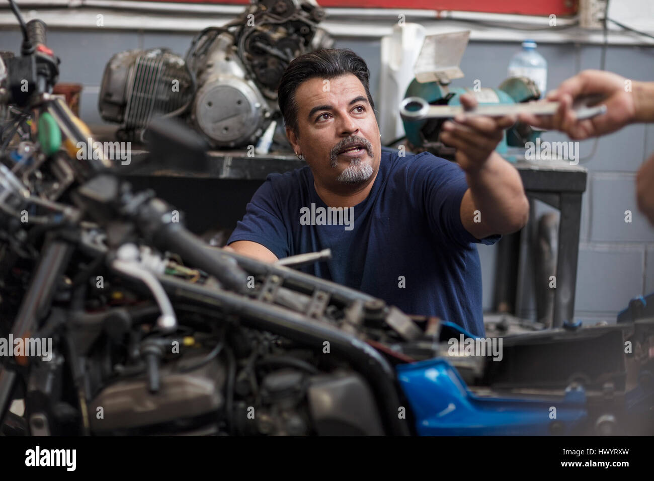 Two mechanics working on motorcycle in workshop Stock Photo - Alamy