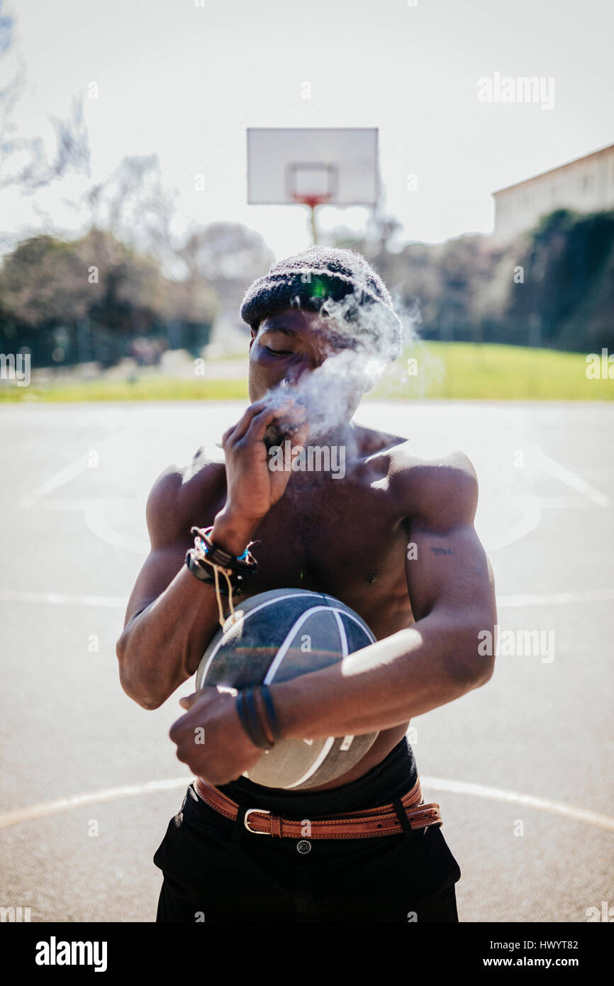 Barechested basketball player on court smoking a joint Stock Photo - Alamy