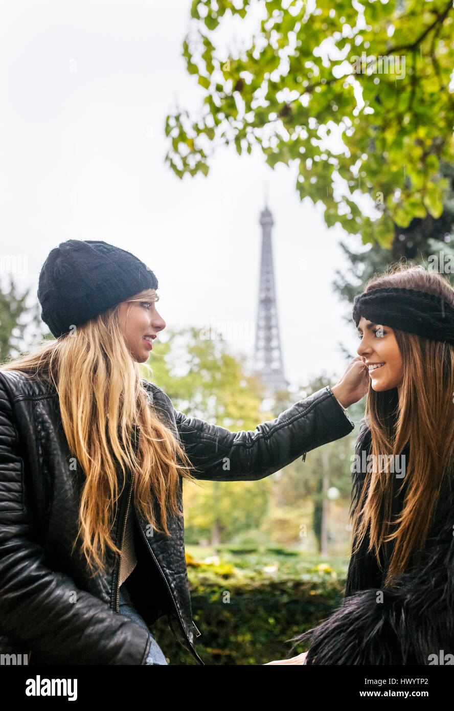 France, Paris, two best friends sitting in a park with the Eiffel Tower ...