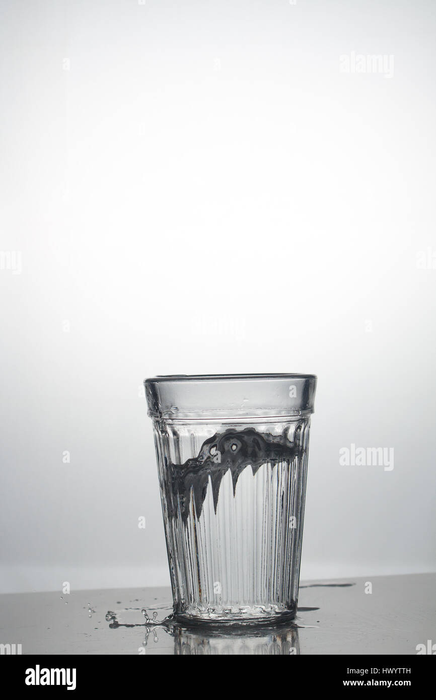 Transparent glass cup with a pouring bubbling cold fresh water with ...