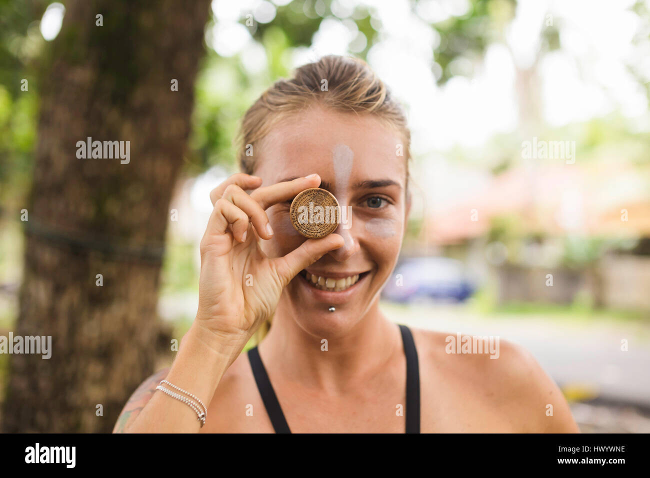 Indonesia, Java, portrait of smiling woman covering her eye with cream ...