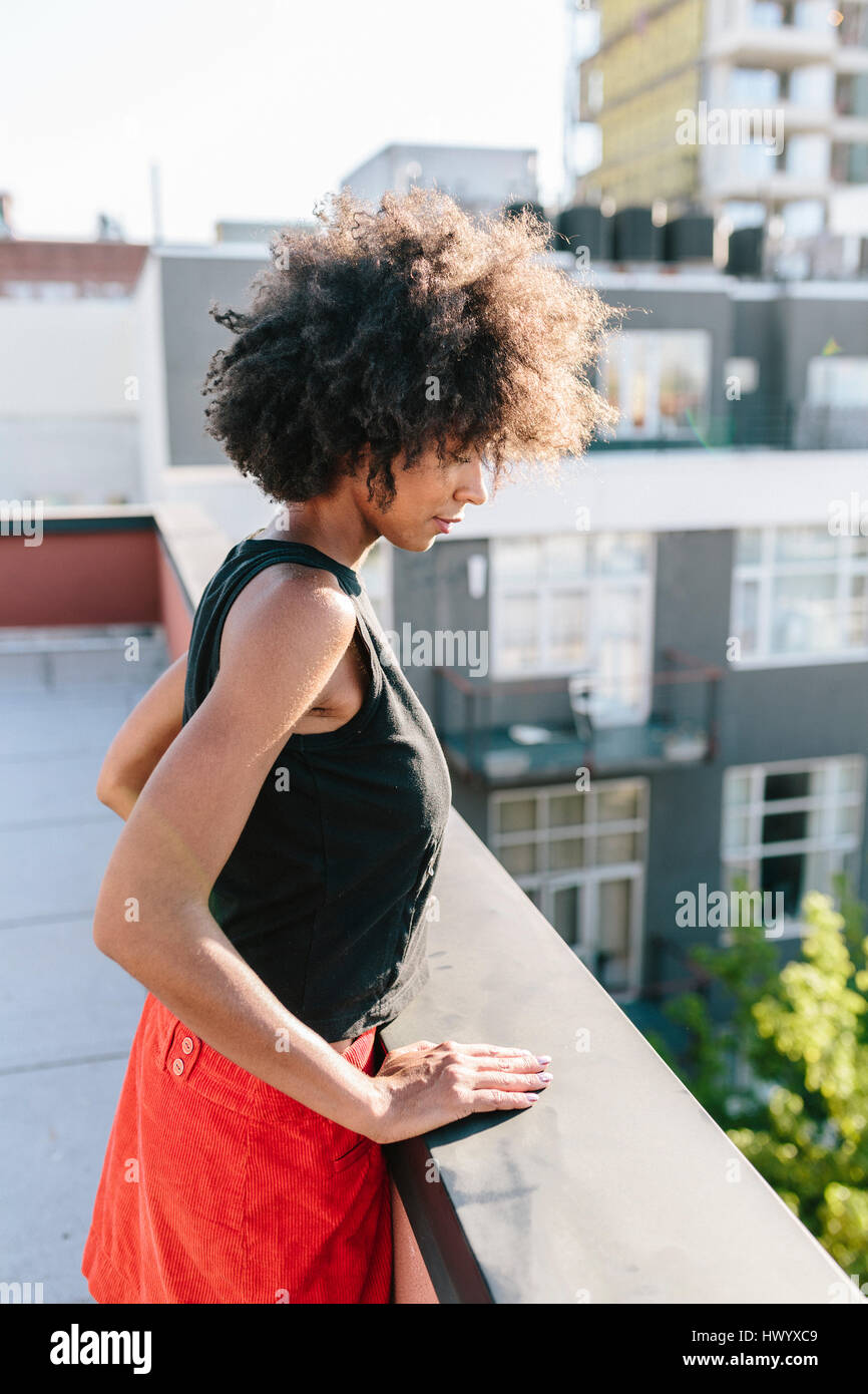 Young woman standing on rooftop in Brookliyn, looking down Stock Photo ...