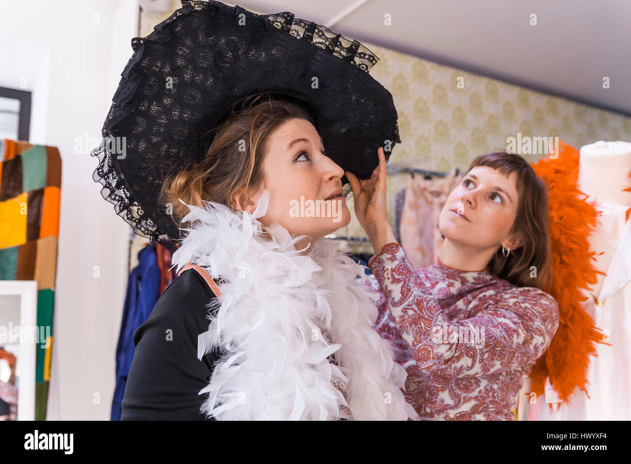 Two women with black hat in a second hand shop Stock Photo - Alamy