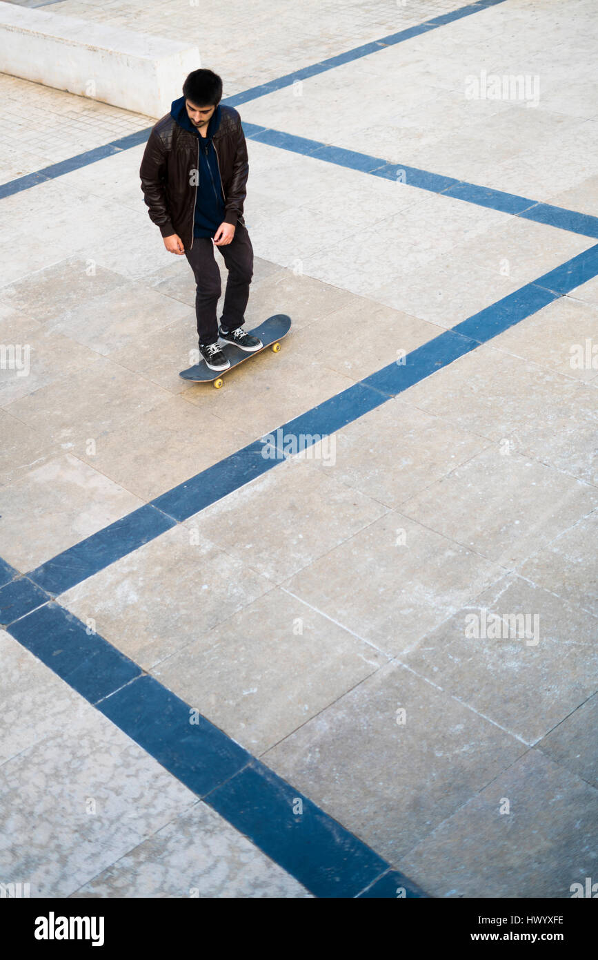 Young man riding skateboard on a square Stock Photo - Alamy