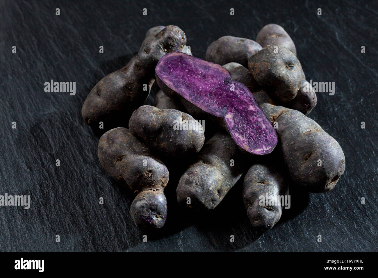 Whole and sliced purple potatoes on slate Stock Photo - Alamy