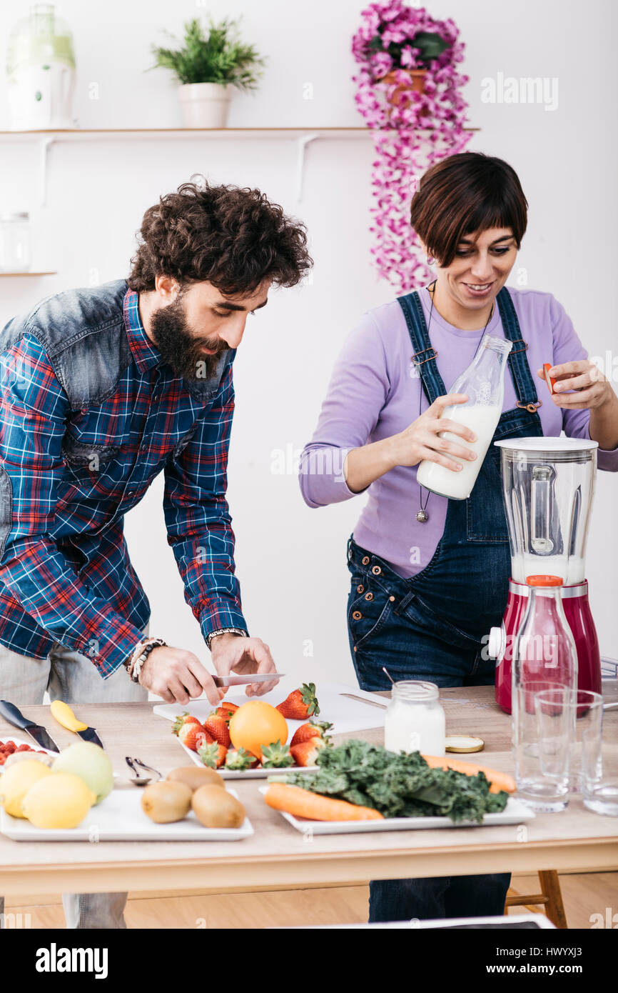 Couple preparing smoothies with fresh fruits and vegetables Stock Photo ...