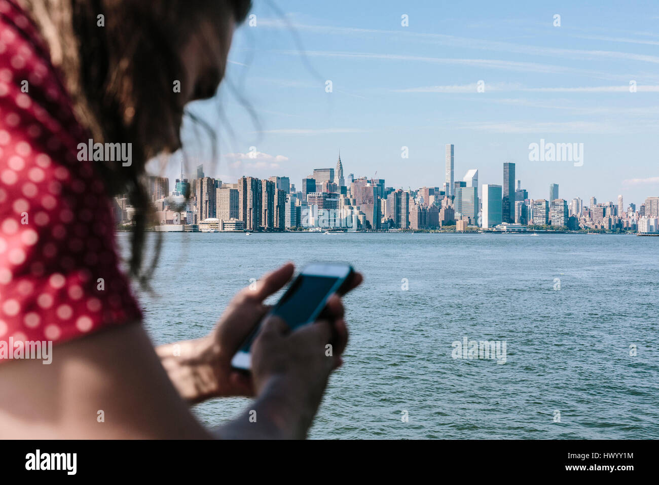 USA, New York City, man using cell phone with Manhattan skyline in ...