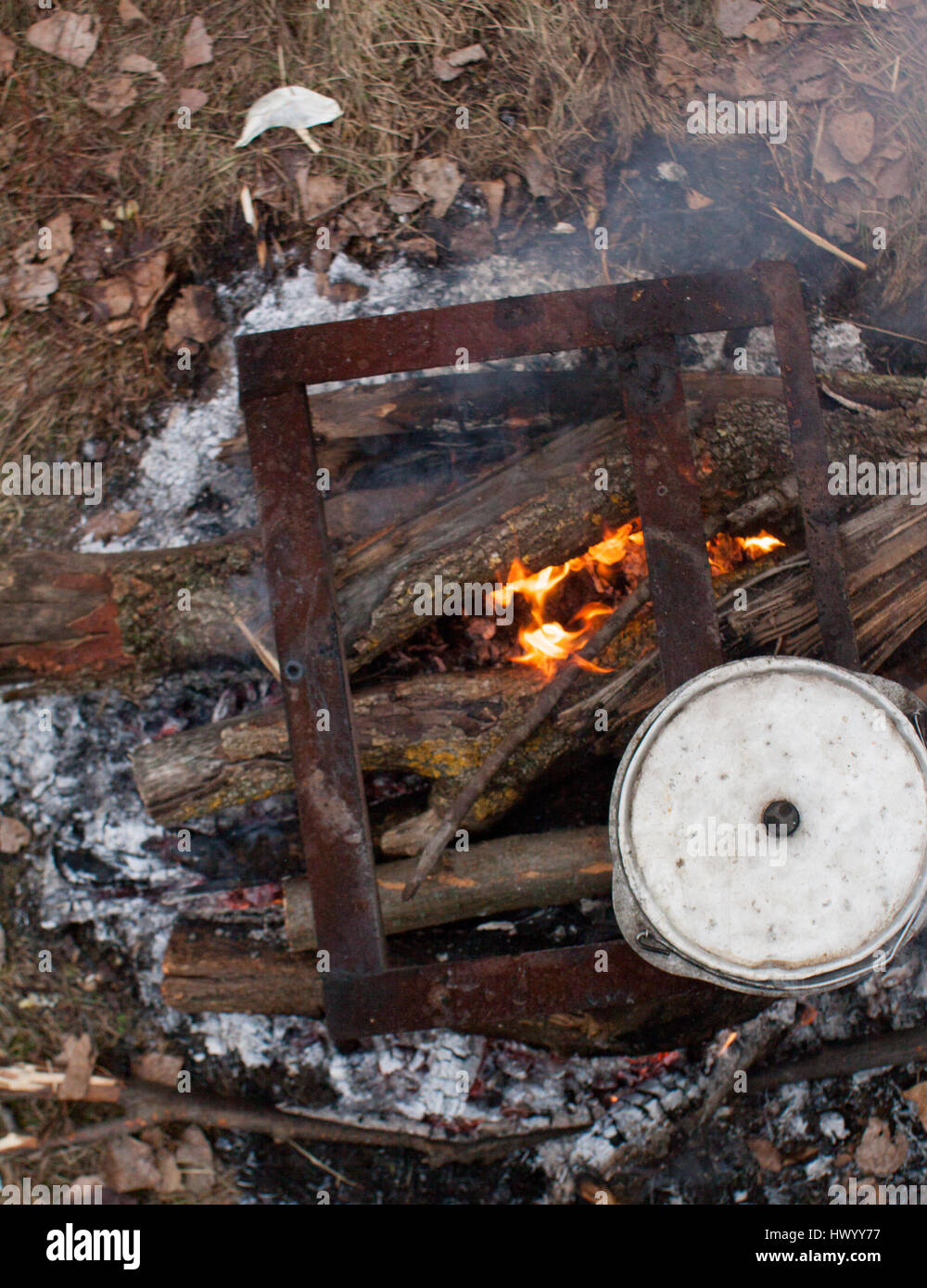 metal pot with a meal basking on burning firewood in the forest ...