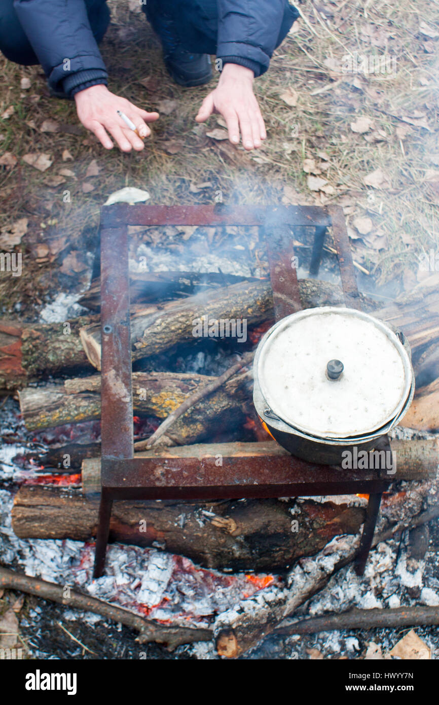 metal pot with a meal basking on burning firewood in the forest ...