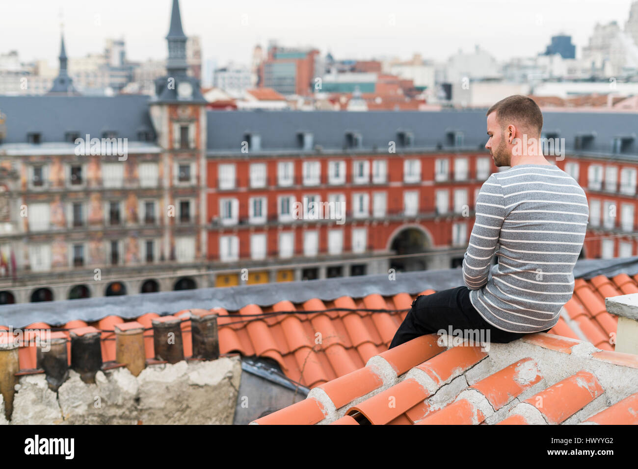 Young man sitting alone on rooftop Stock Photo - Alamy