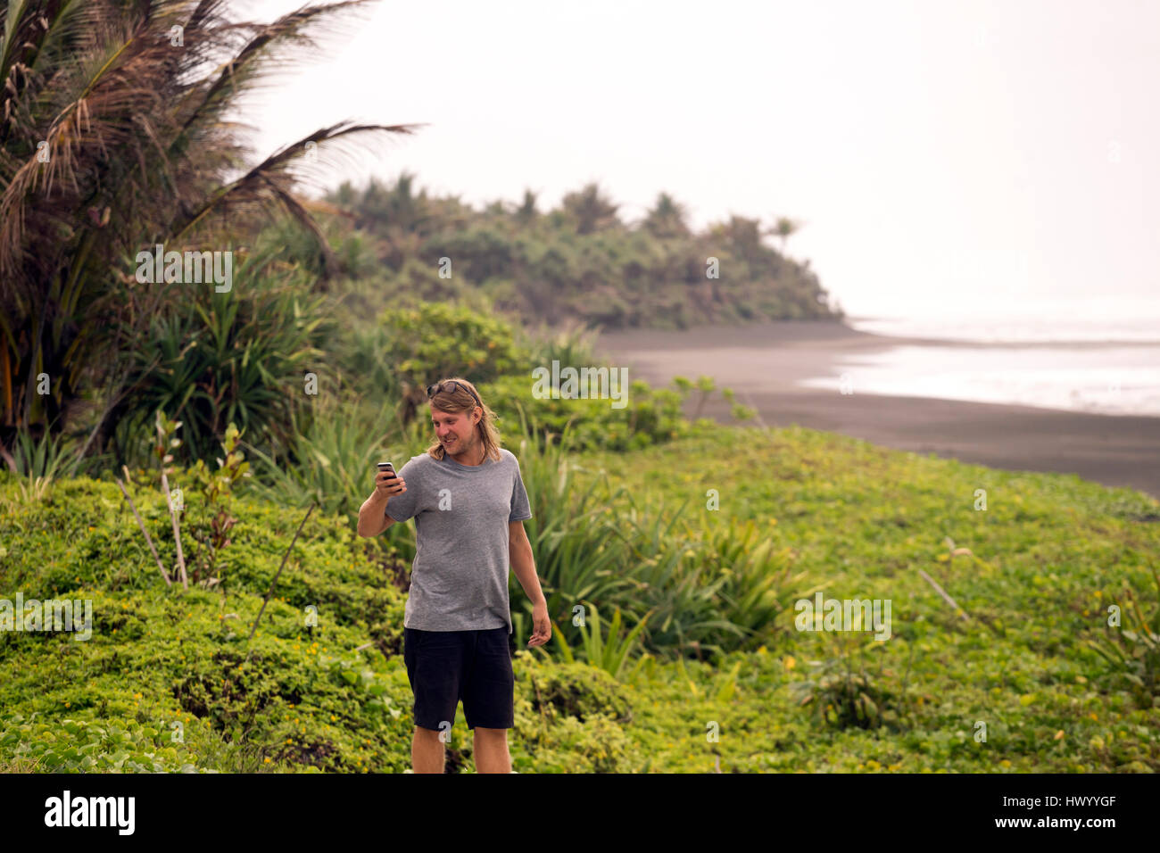 Indonesia, Java, man using cell phone at the coast Stock Photo - Alamy