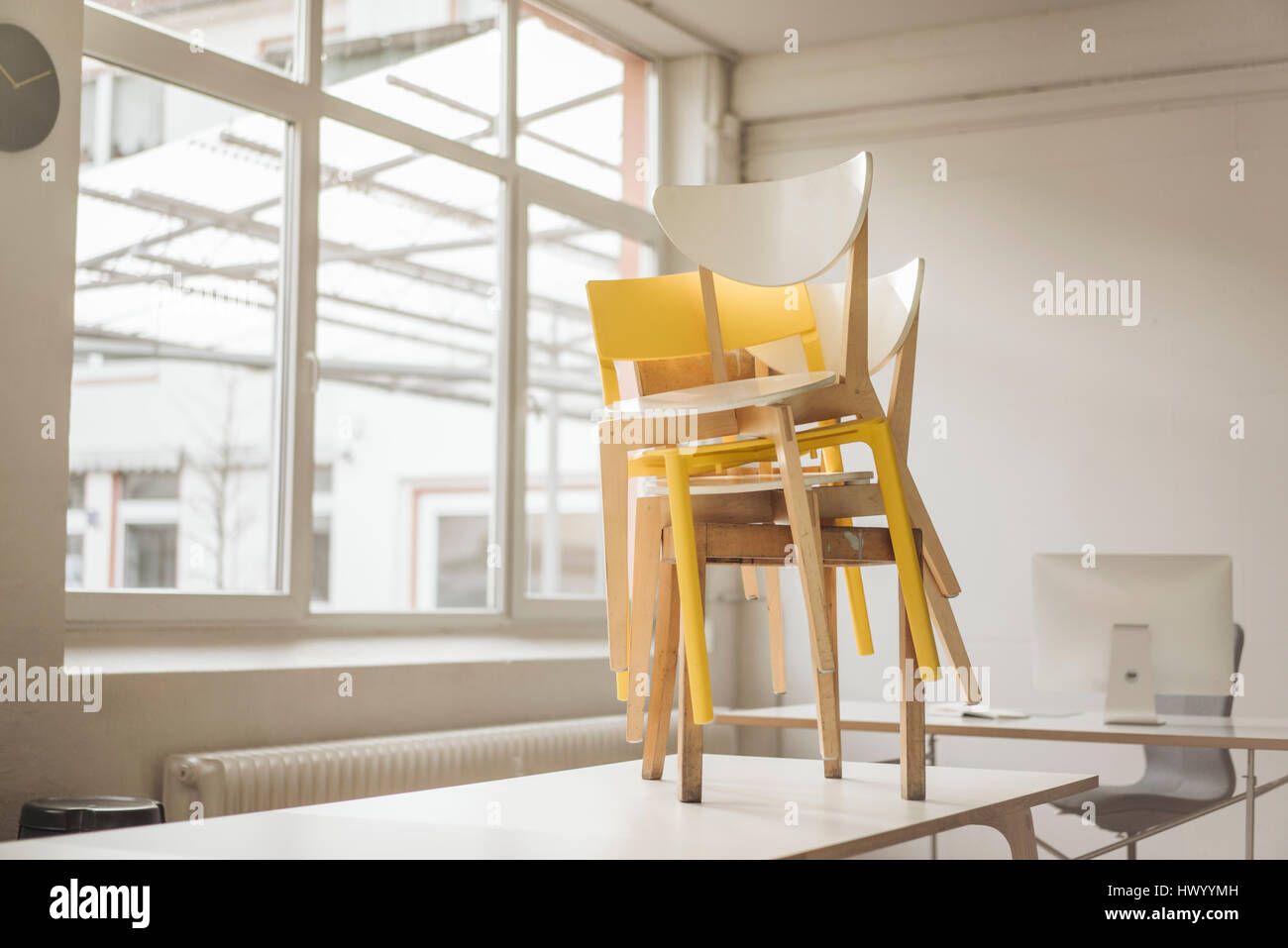 Stack of chairs standing on meeting table in a loft Stock Photo - Alamy
