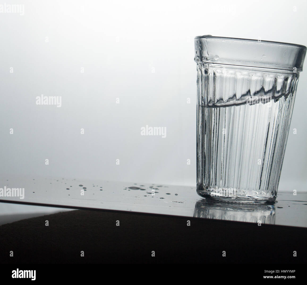 Transparent glass cup with a pouring bubbling cold fresh water with ...