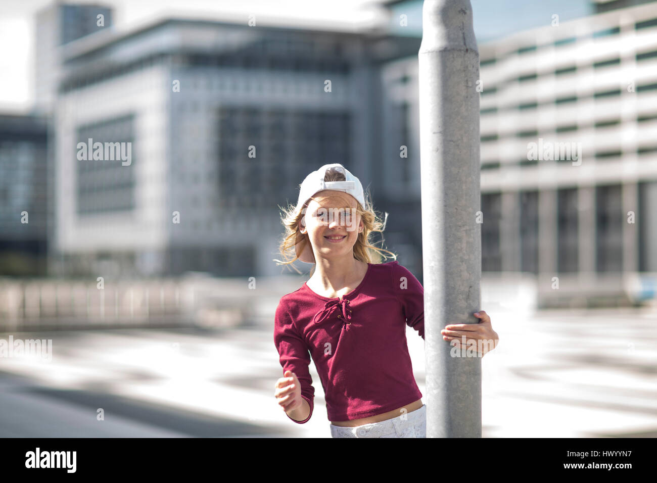 Smiling girl holding onto lamp post Stock Photo - Alamy